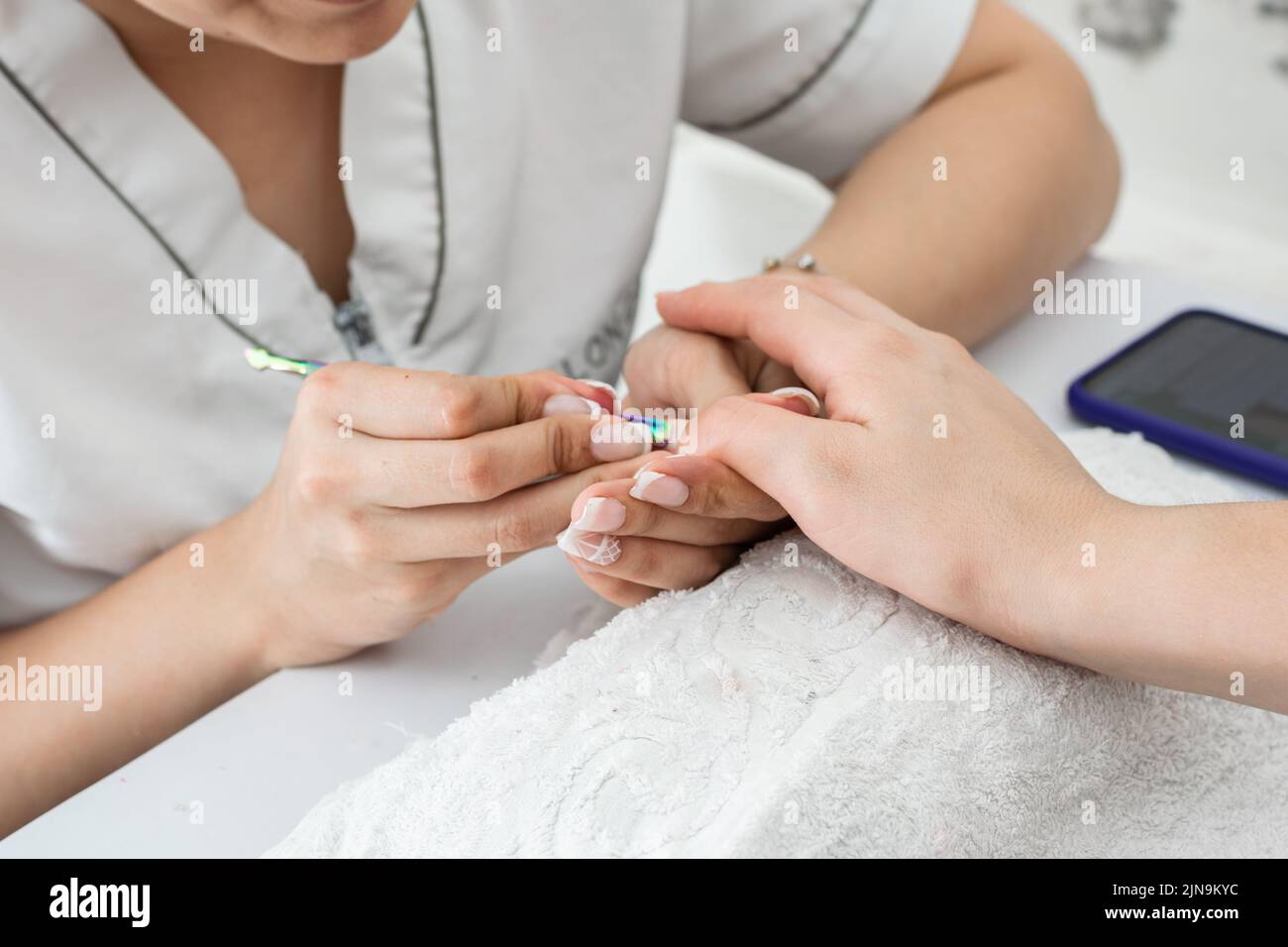 latina manicurist working at home, cleaning a girl's nails with the ...