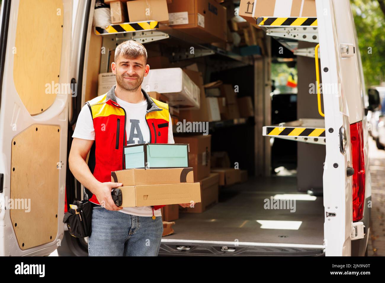 The happy courier in front of the work car has taken the packages and ...