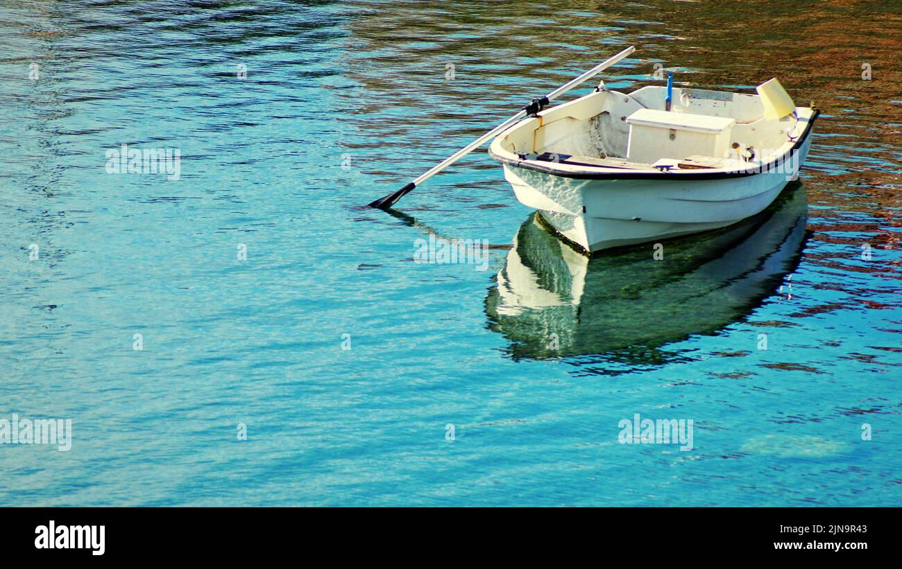 A white small boat in the transparent lake water Stock Photo - Alamy