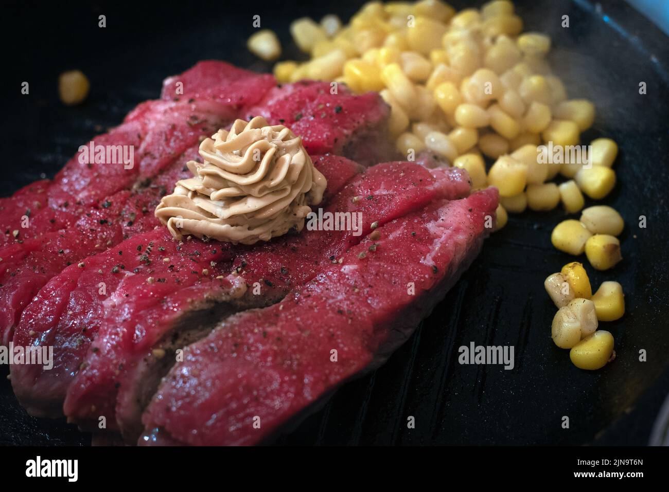 Rare beef steak on a hot plate with corn kernels Stock Photo - Alamy