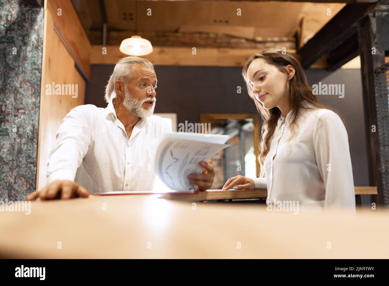 Senior man, manager making plans together with secretary, reading some ...