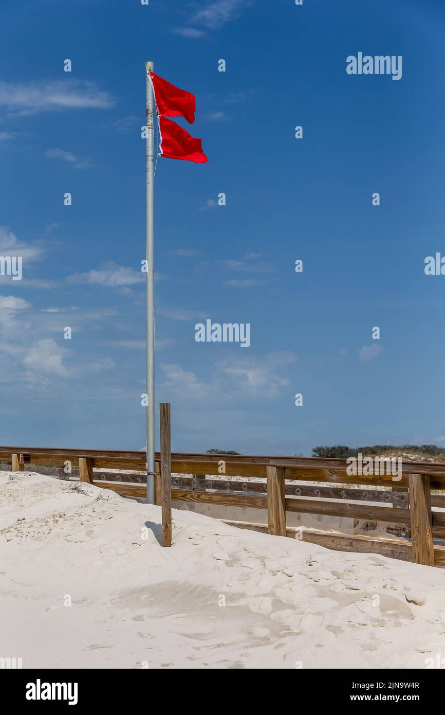 Double red flags against a blue sky indicating that the beach is closed ...