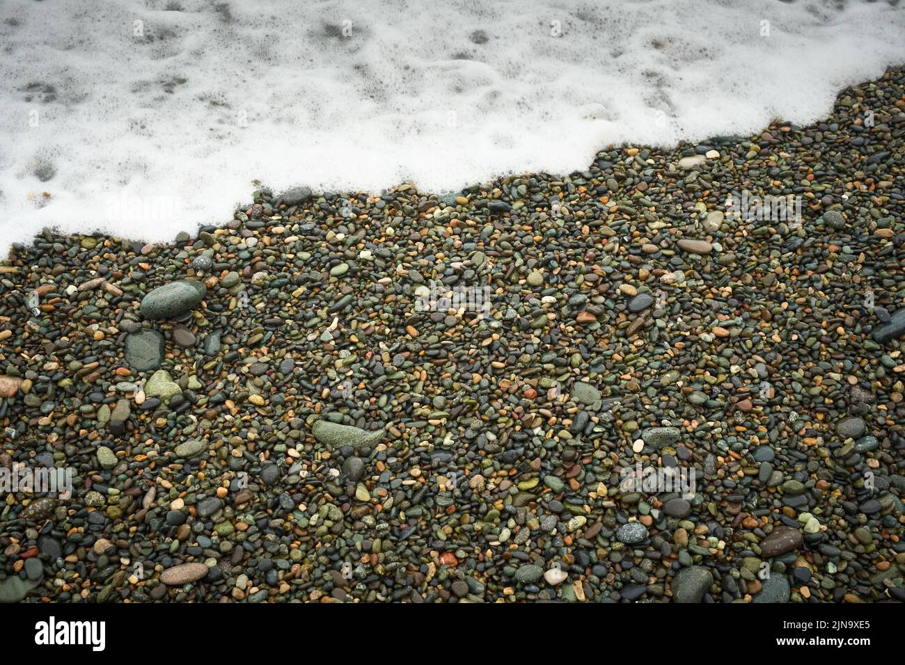 Sea waves wash over a pebble beach made of natural rounded gravel Stock ...