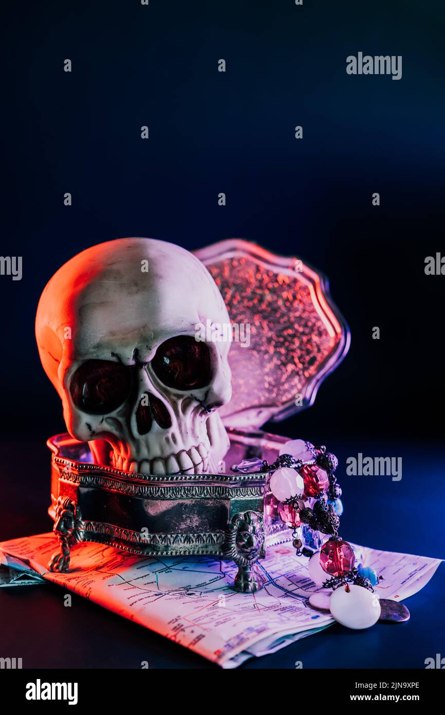 Human skull and treasure in copper vintage box on the map in neon red ...