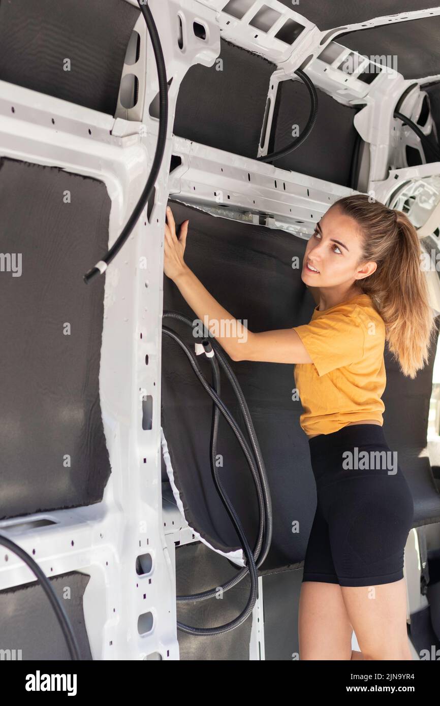 Vertical view of young woman on a ponytail working installing the ...