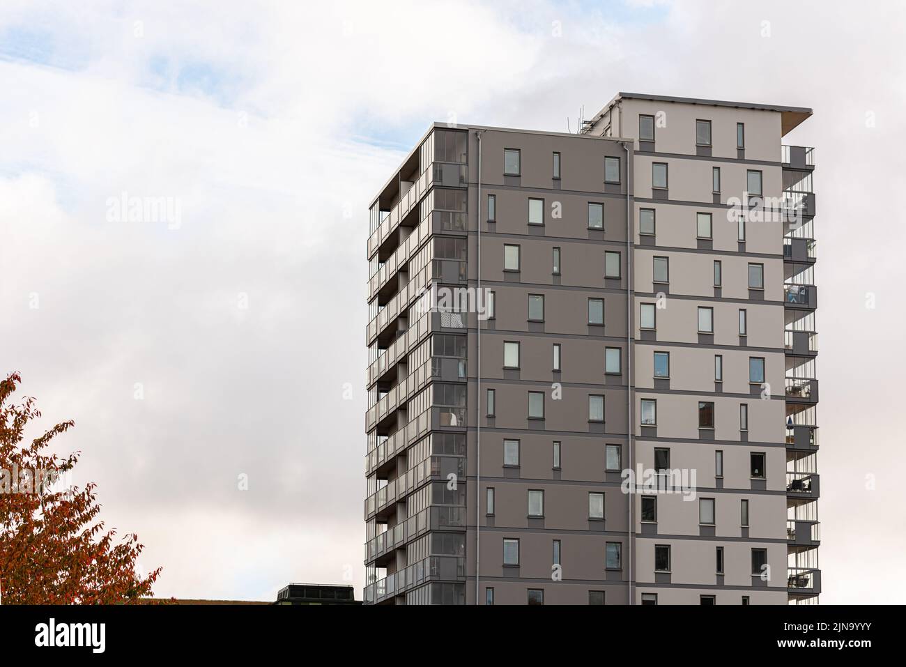 a Eleven-storey high grey apartment building against sky background ...