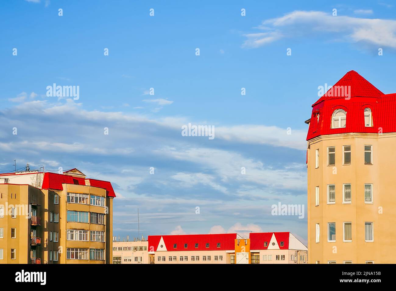 Residential high-rise building with red tiled roof against blue sky ...