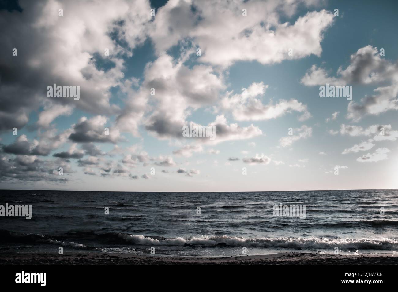 Cloudy day at the beach with cool colors. White, grey, shady clouds and ...