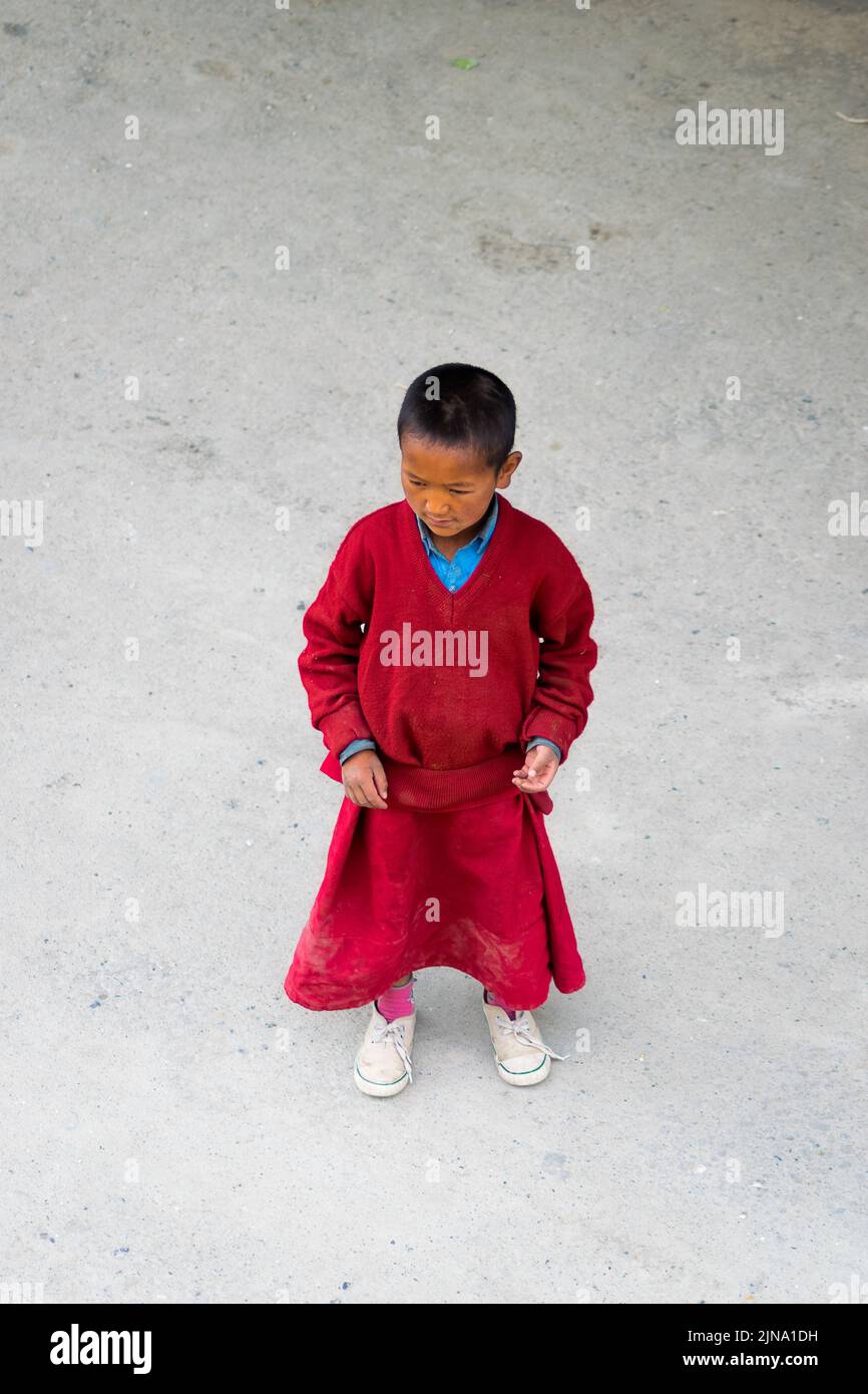 A vertical shot of a young monk dressed in dusty red uniform in Kee ...