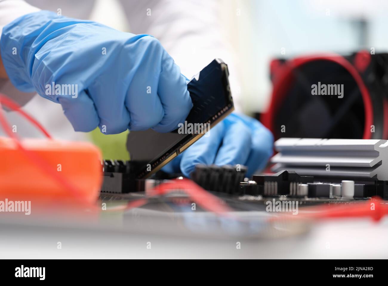 Repair engineer holds RAM chip with hands and inserts RAM of computer ...