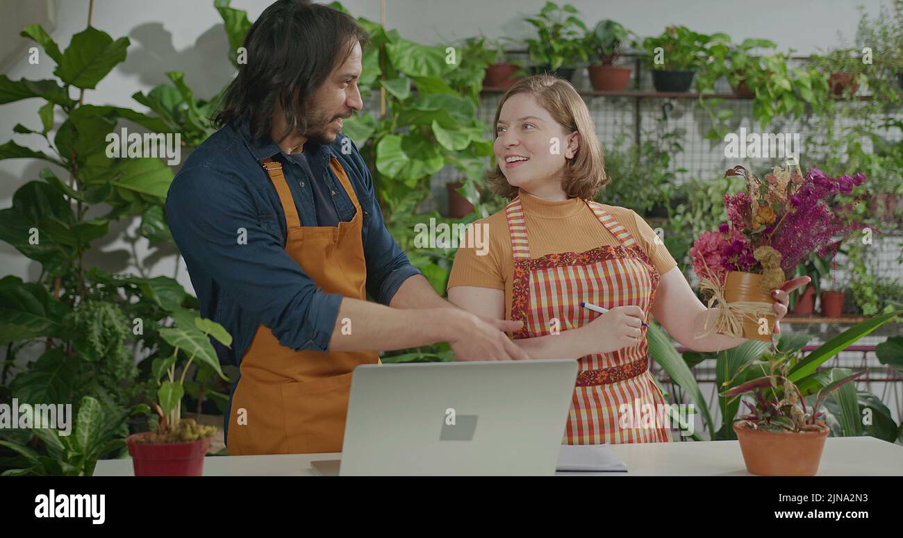 Young entrepreneurs managing online orders at small business flower ...