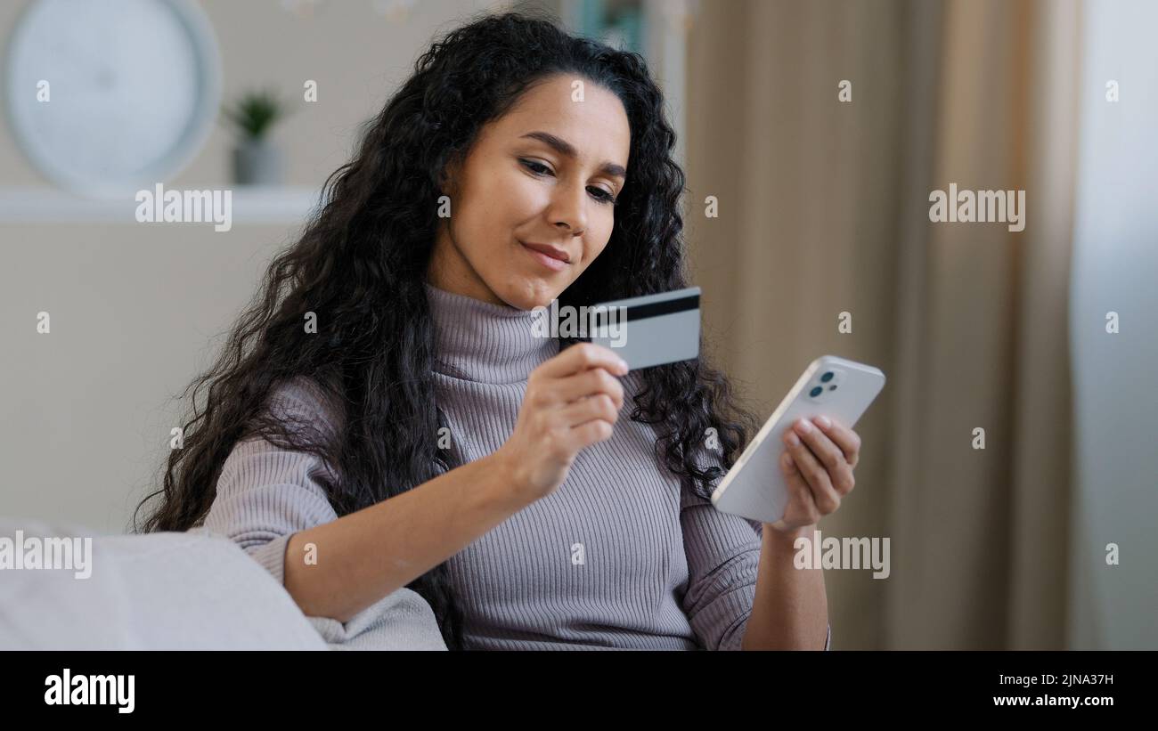 Smiling young hispanic woman hold phone and credit card happy girl ...