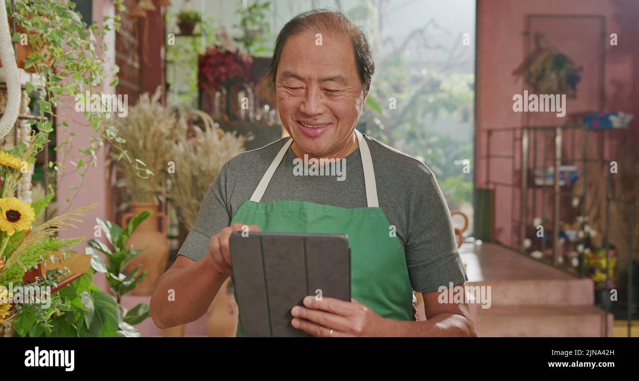 Portrait of a happy Asian American business owner holding tablet ...