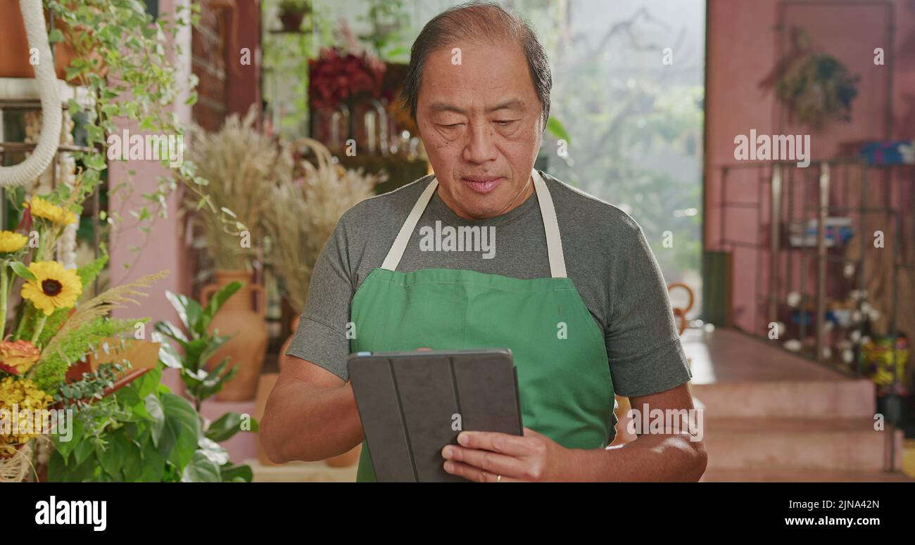 Portrait of a happy Asian American business owner holding tablet ...
