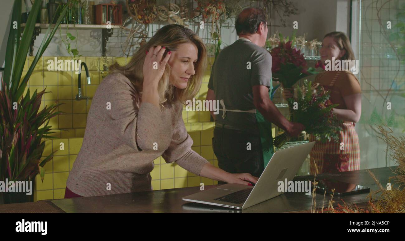 Female entrepreneur owner of retail store looking at laptop computer ...