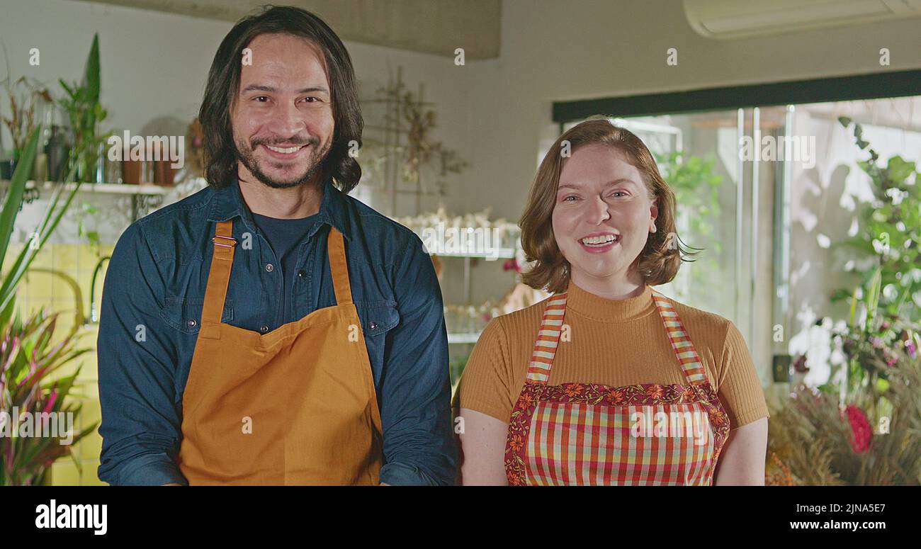 Portrait of two floriculture professionals inside flower shop. Male and ...