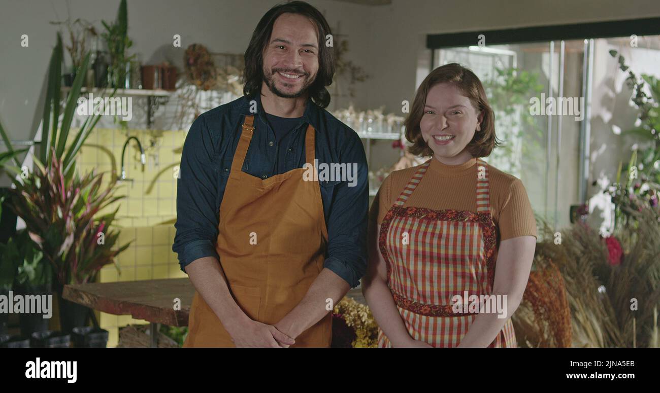 Portrait of two floriculture professionals inside flower shop. Male and ...