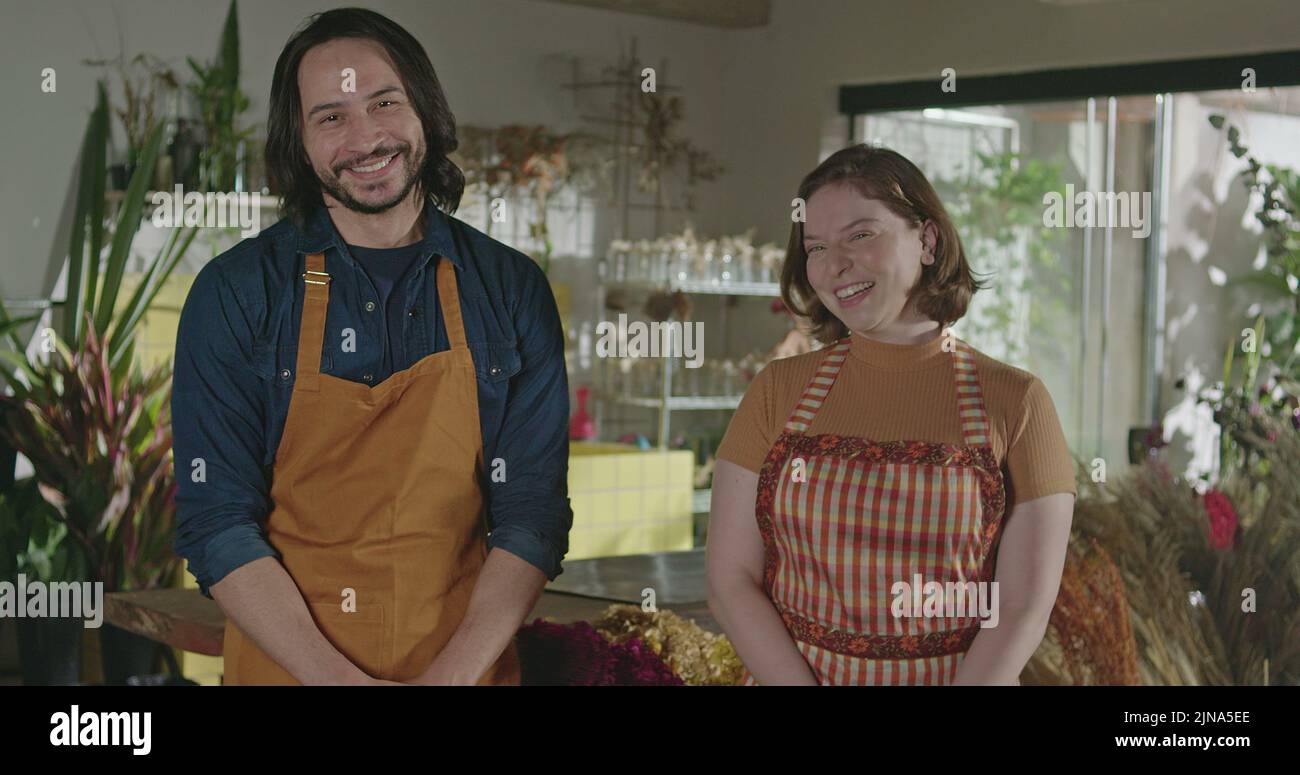 Portrait of two floriculture professionals inside flower shop. Male and ...