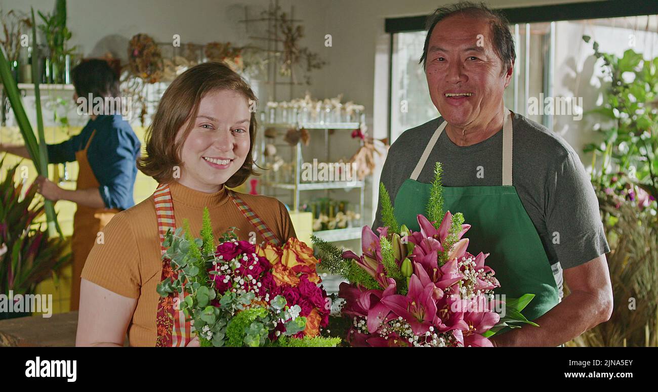 Flower shop employees holding flowers in conversation. A Happy local ...