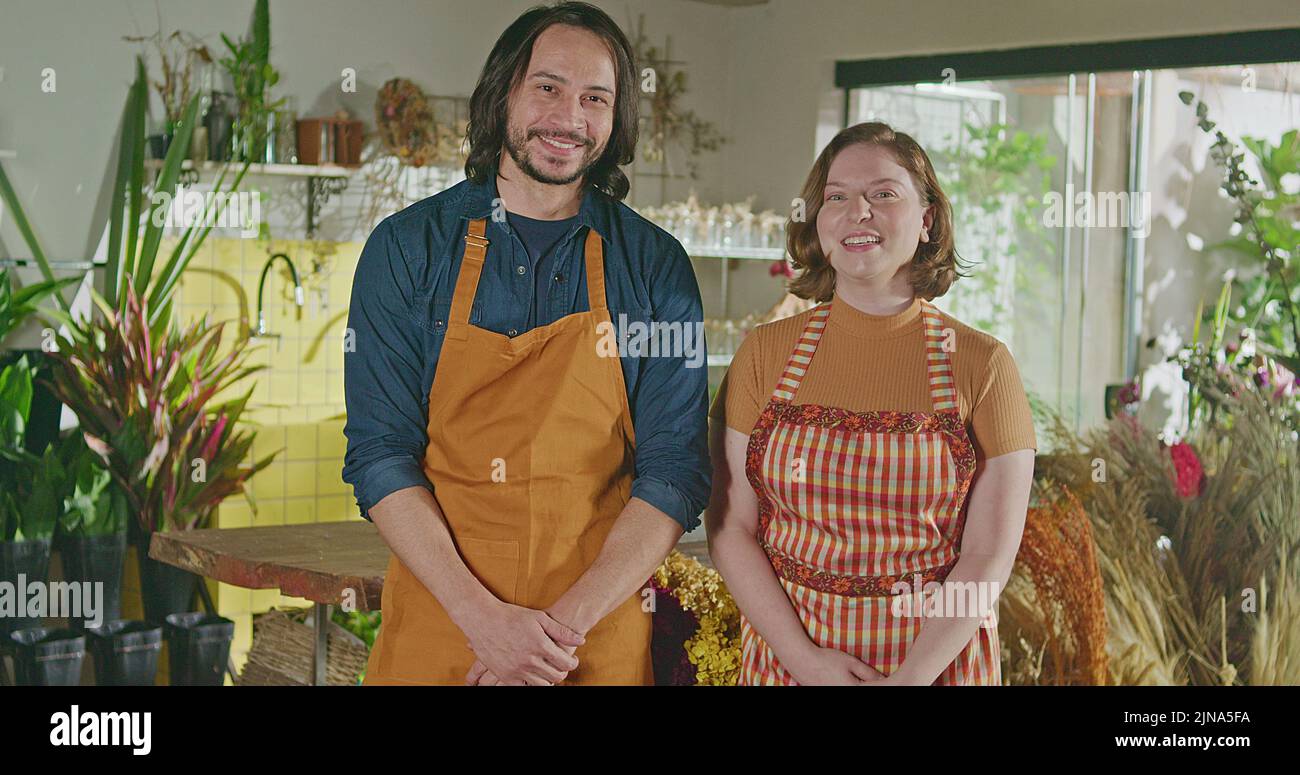 Portrait of two floriculture professionals inside flower shop. Male and ...