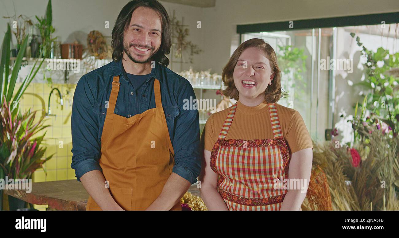 Portrait of two floriculture professionals inside flower shop. Male and ...