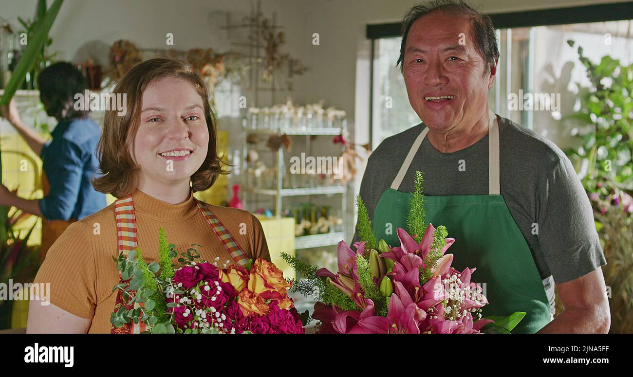 Flower shop employees holding flowers in conversation. A Happy local ...