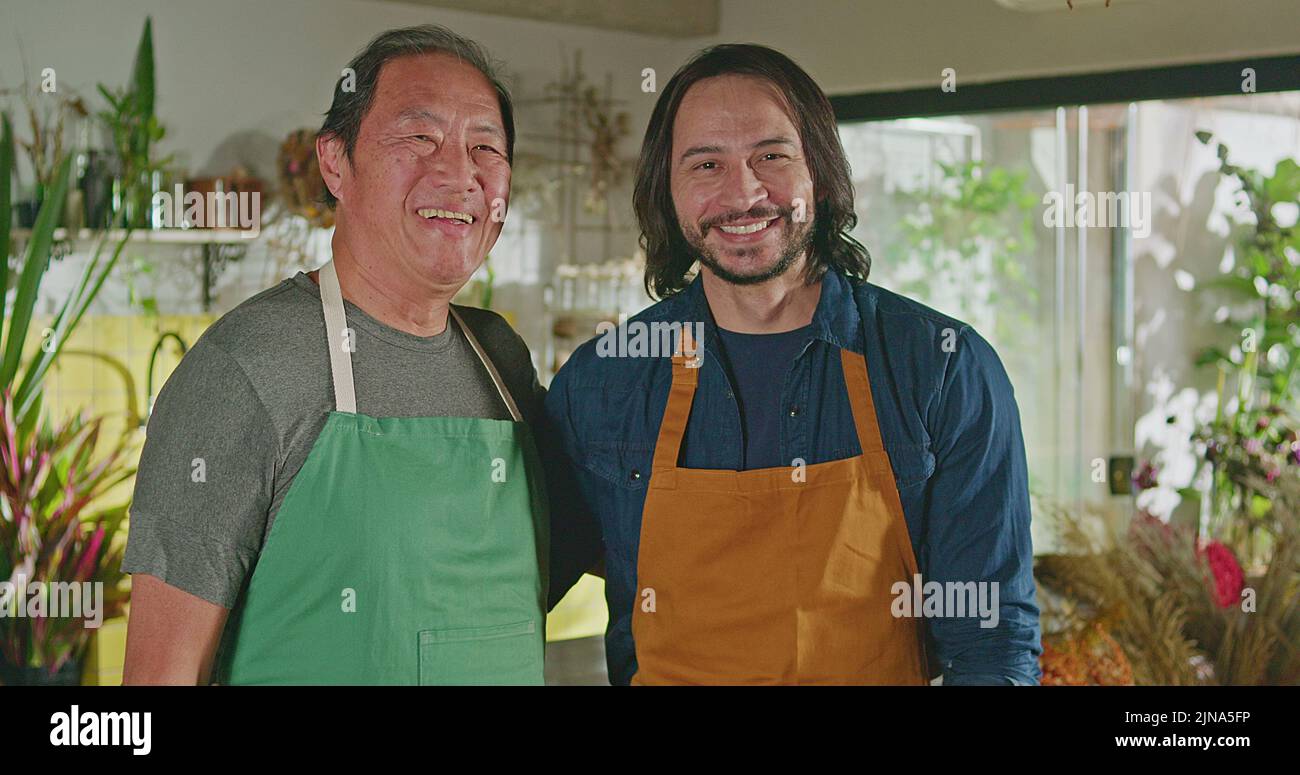 Two male employees of floriculture store standing smiling. An older and ...