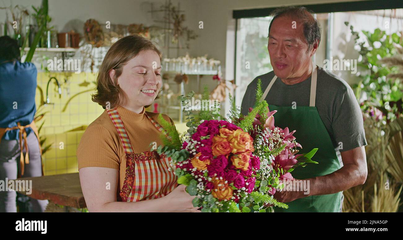 Flower shop employees holding flowers in conversation. A Happy local ...