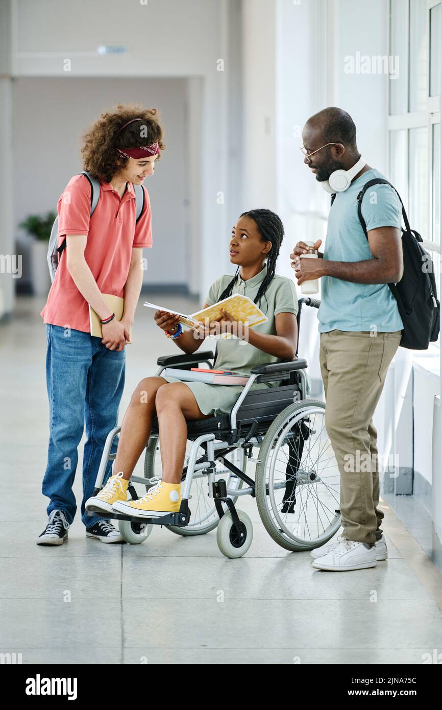 African girl with disability sitting on wheelchair with opened book and ...