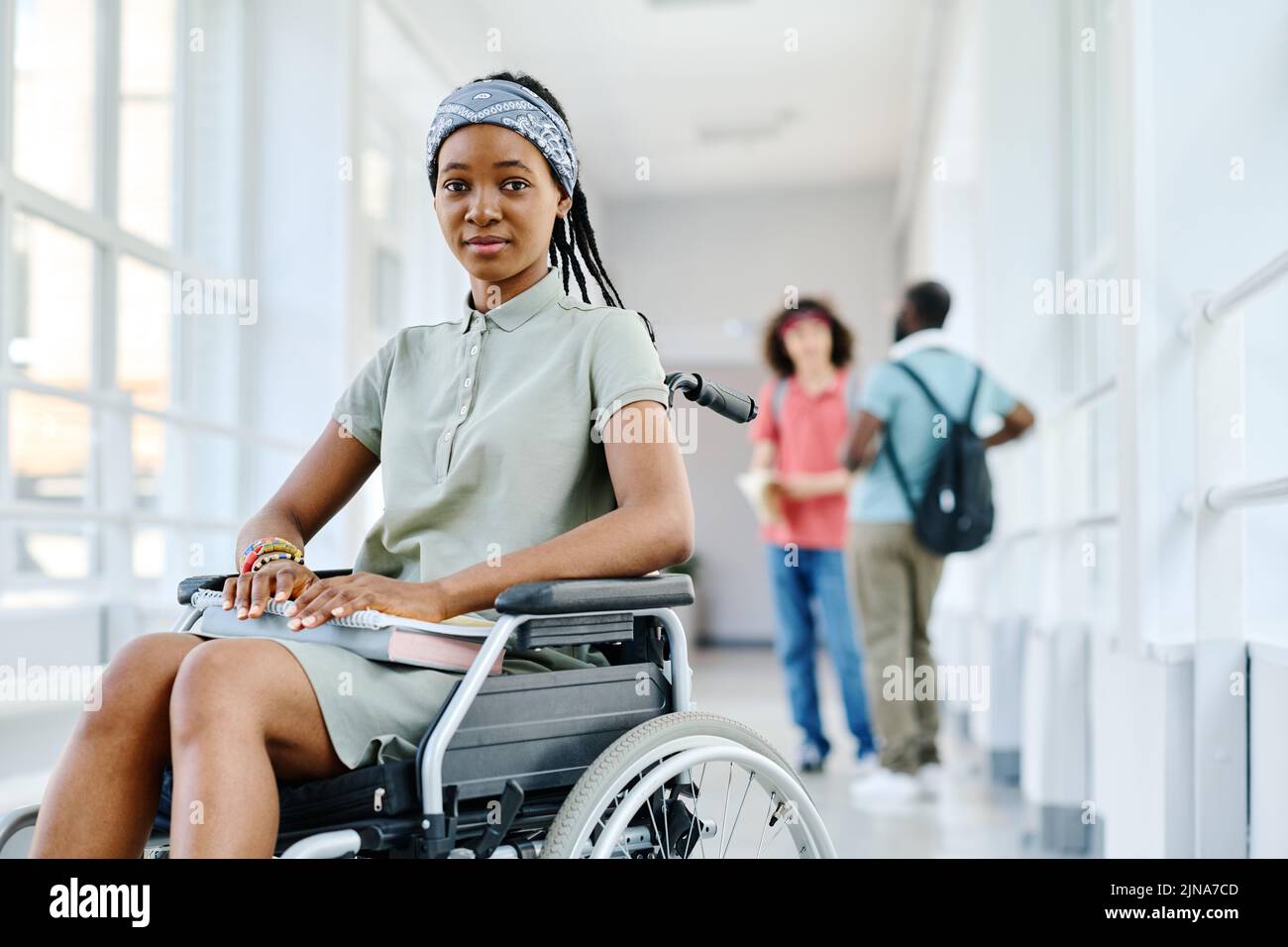 Portrait of African teenage girl sitting in wheelchair and looking at ...