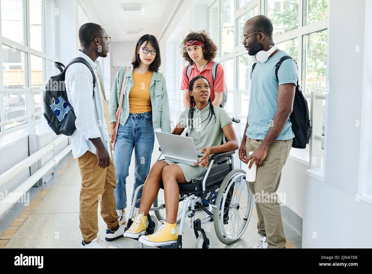 Girl with disability using laptop and talking to her friends during ...