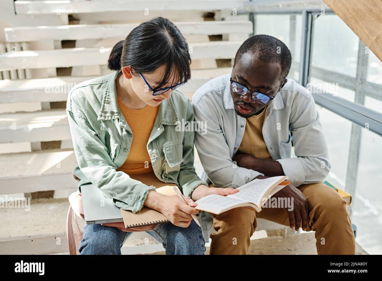 Couple of students preparing for the exams together reading a book ...