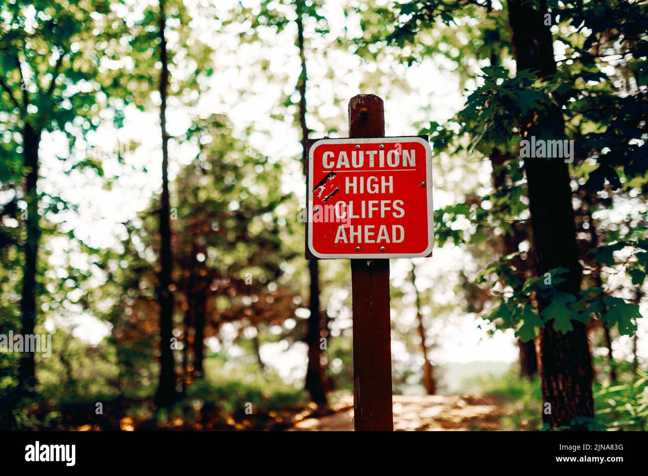 A red square-shaped caution sign in a forest on a sunny day Stock Photo ...