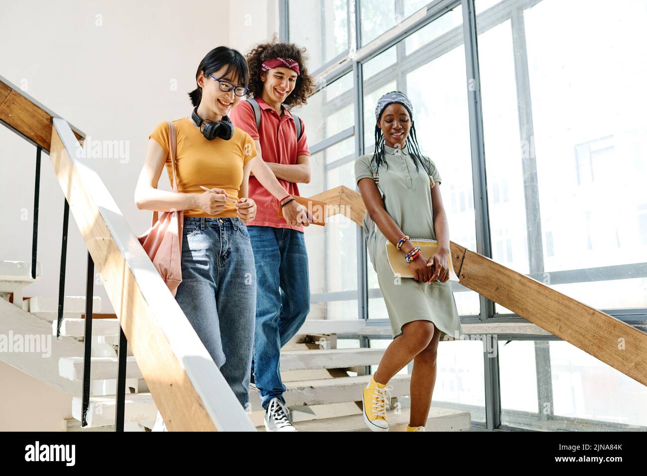 Group of happy students going down the stairs after lesson at school ...