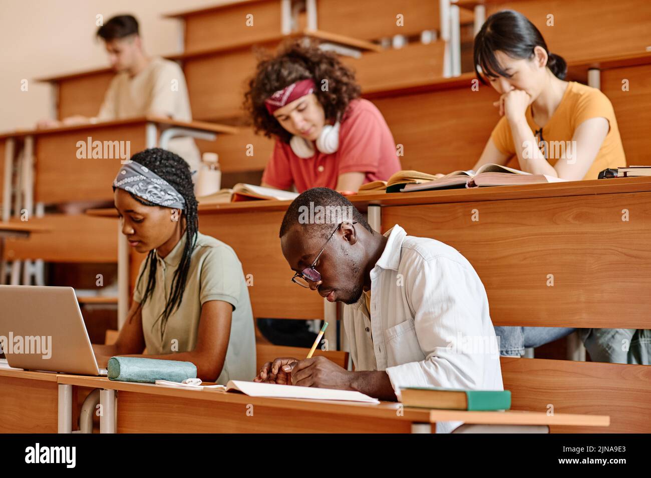Multiethnic group of students sitting at lecture at university and ...