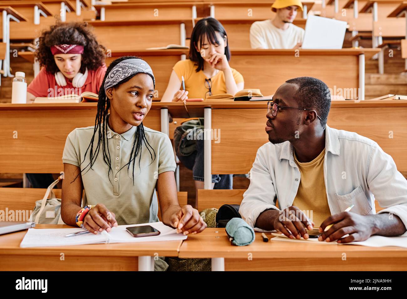 African students talking to each other while sitting at desk at ...