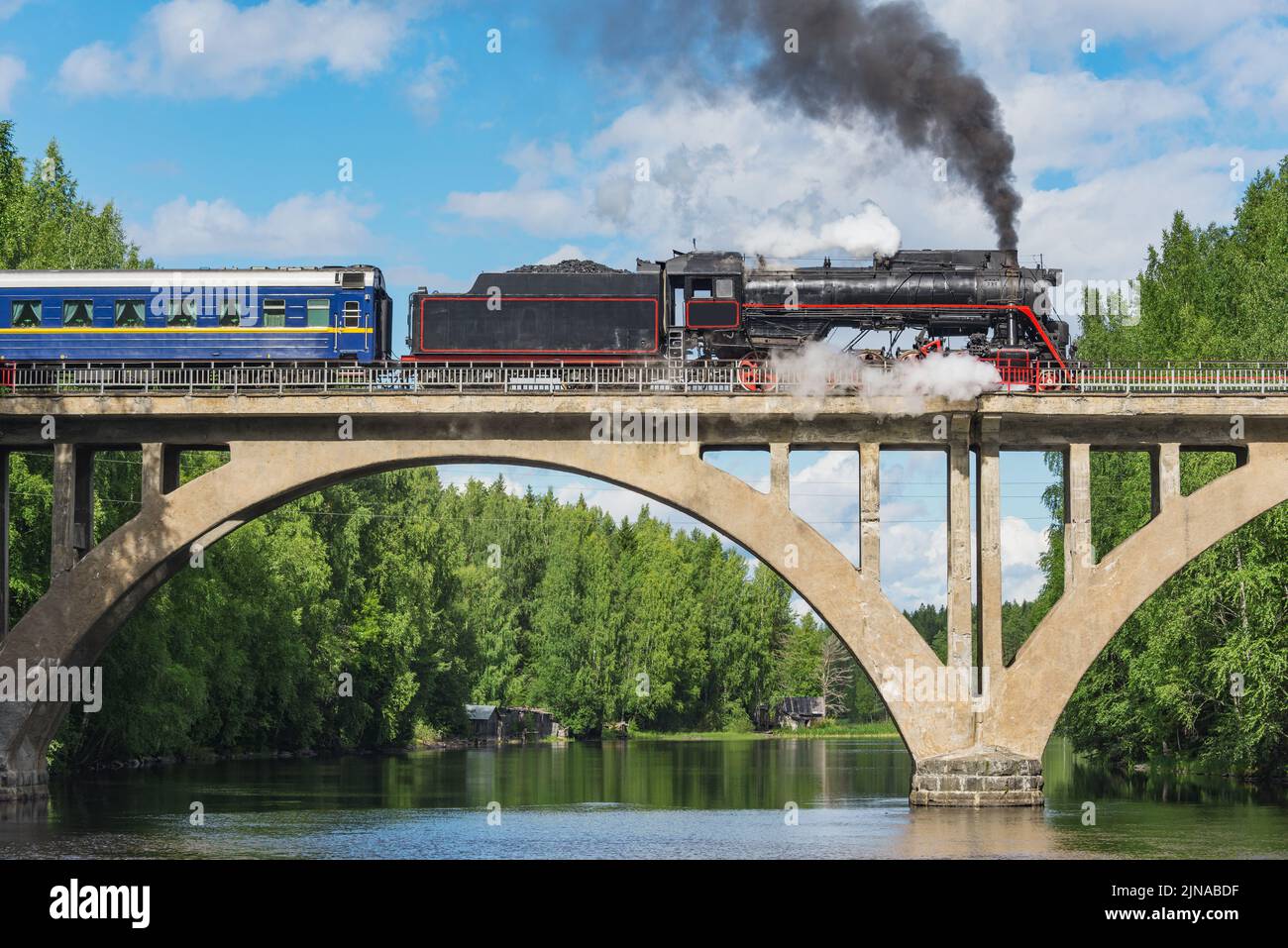 Retro steam train moves above the river Stock Photo - Alamy
