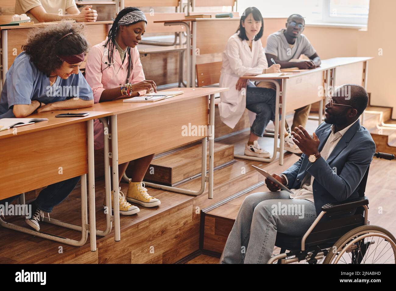 African teacher with disability sitting on wheelchair and reading ...