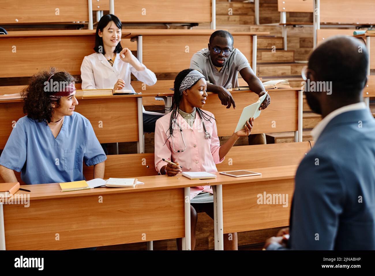 Group of medical students sitting at desks at lecture and discussing ...