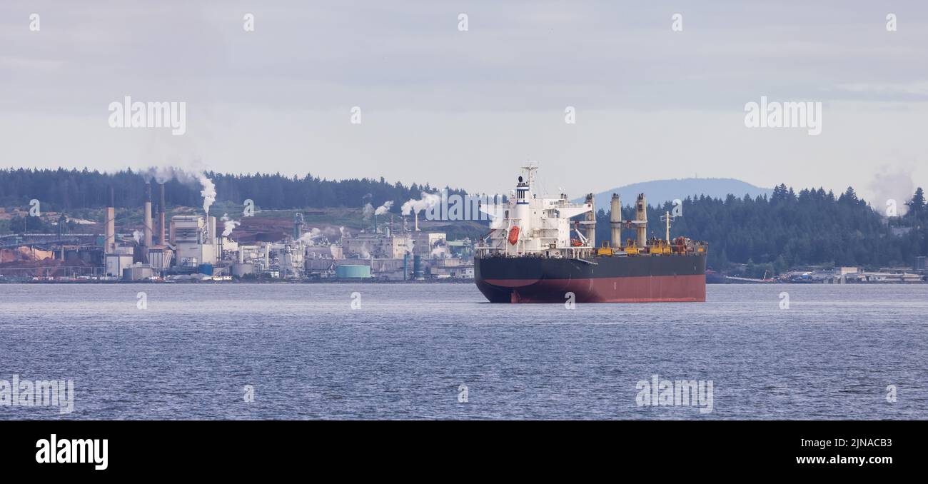 Industrial Processing Plant and Container Ship passing by on a cloudy ...