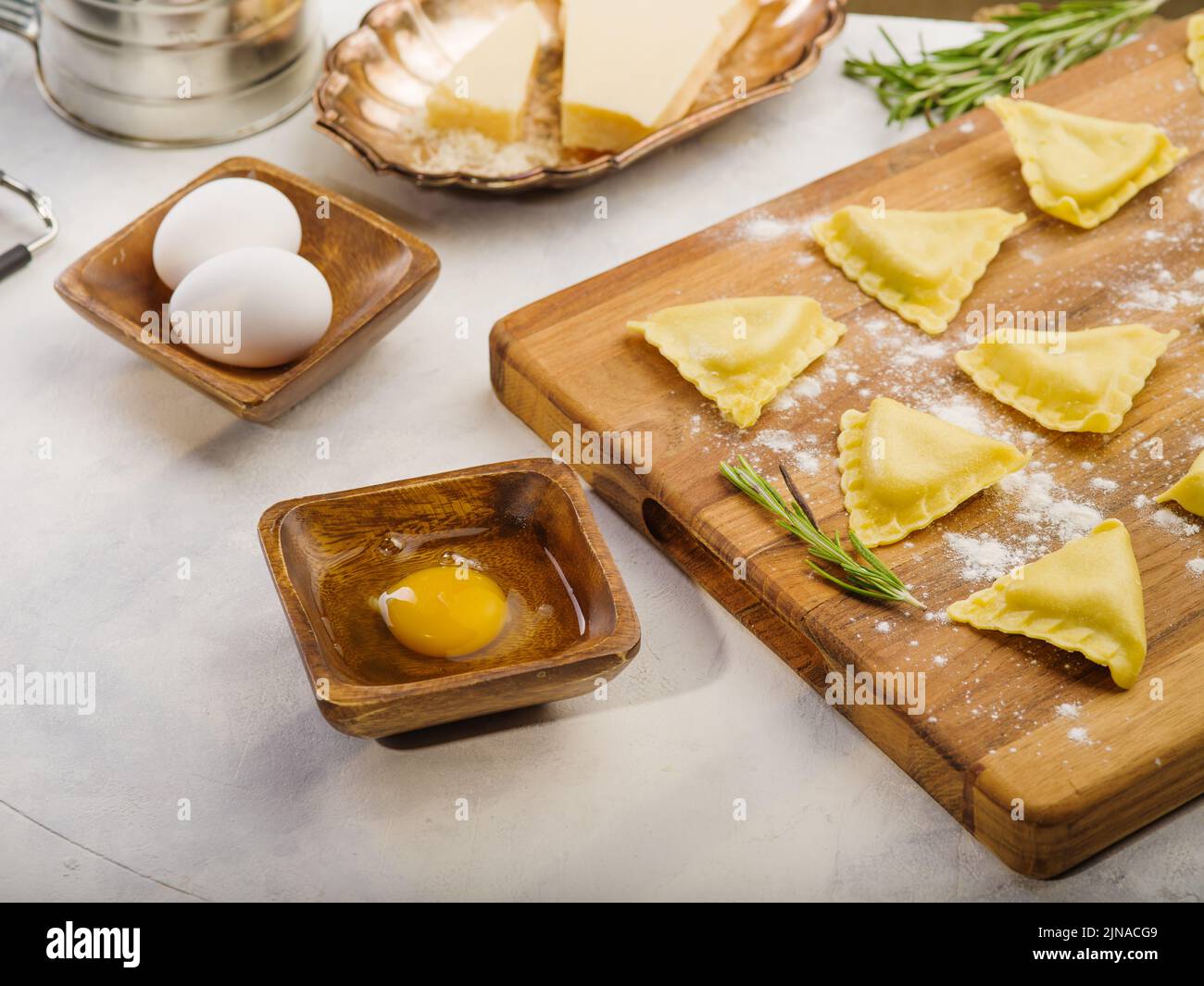 Triangle shaped homemade ravioli on a cutting board and ingredients on ...