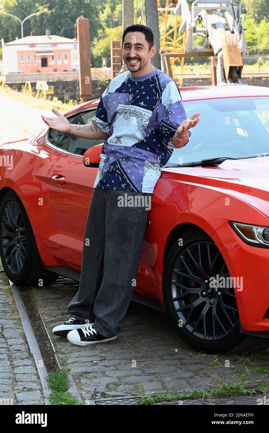 Cologne, Germany. 10th Aug, 2022. Rapper Eko Fresh leans against a red ...