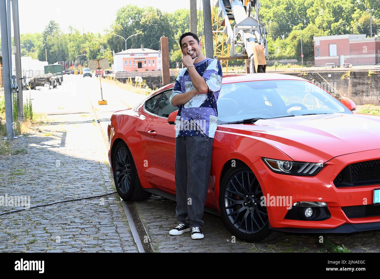 Cologne, Germany. 10th Aug, 2022. Rapper Eko Fresh leans on a red Ford ...