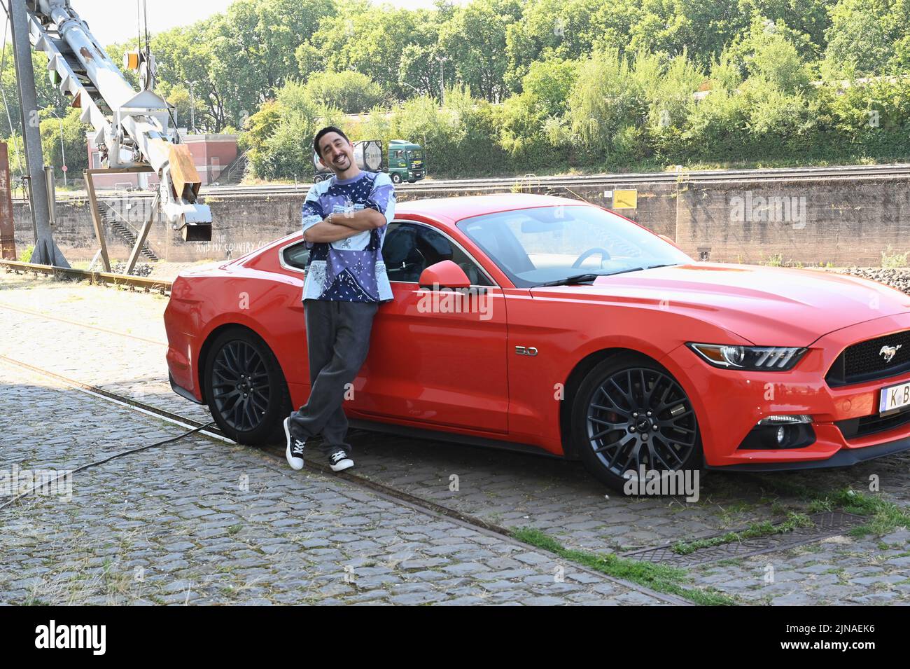 Cologne, Germany. 10th Aug, 2022. Rapper Eko Fresh leans against a red ...