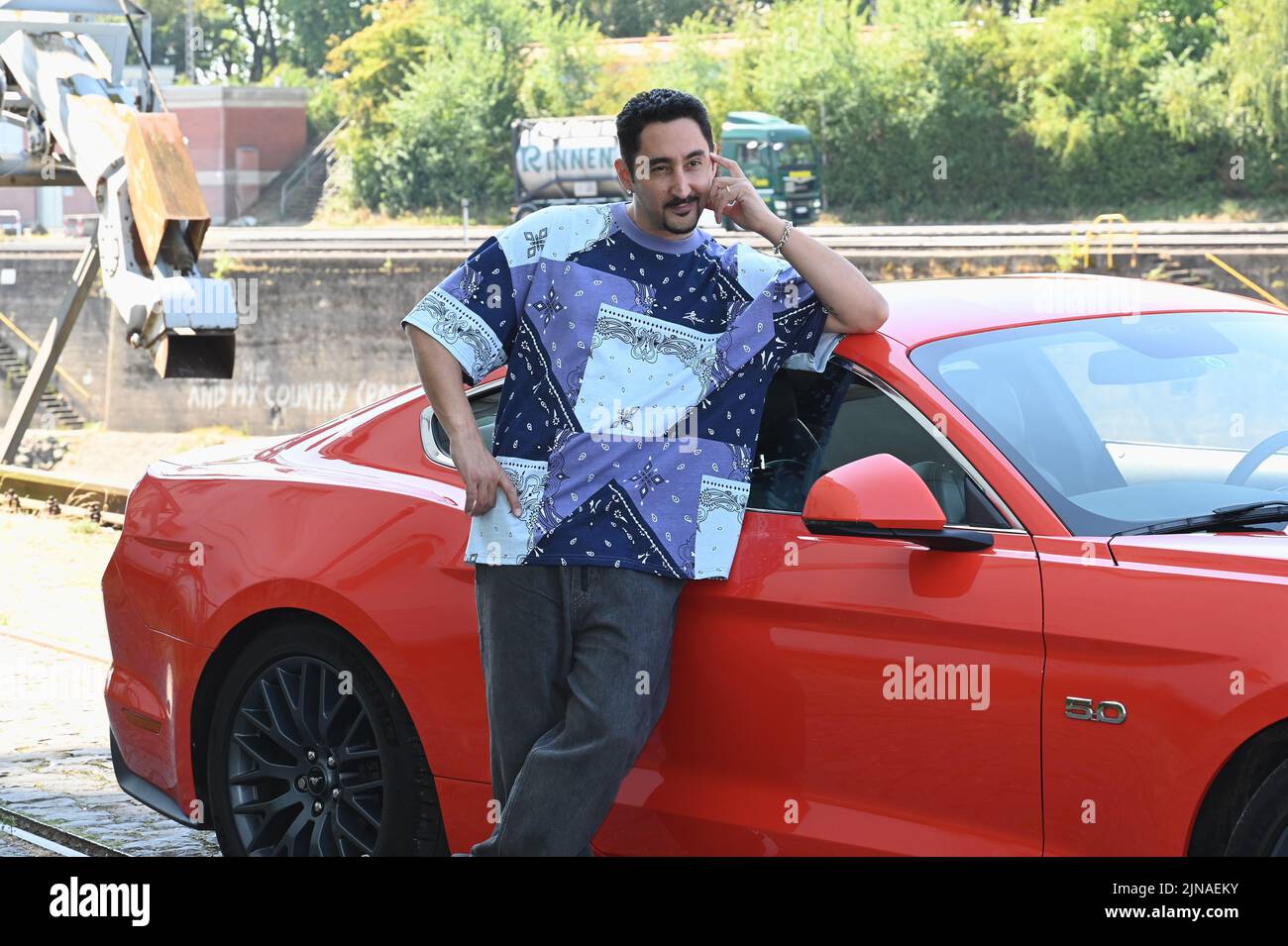Cologne, Germany. 10th Aug, 2022. Rapper Eko Fresh leans against a red ...