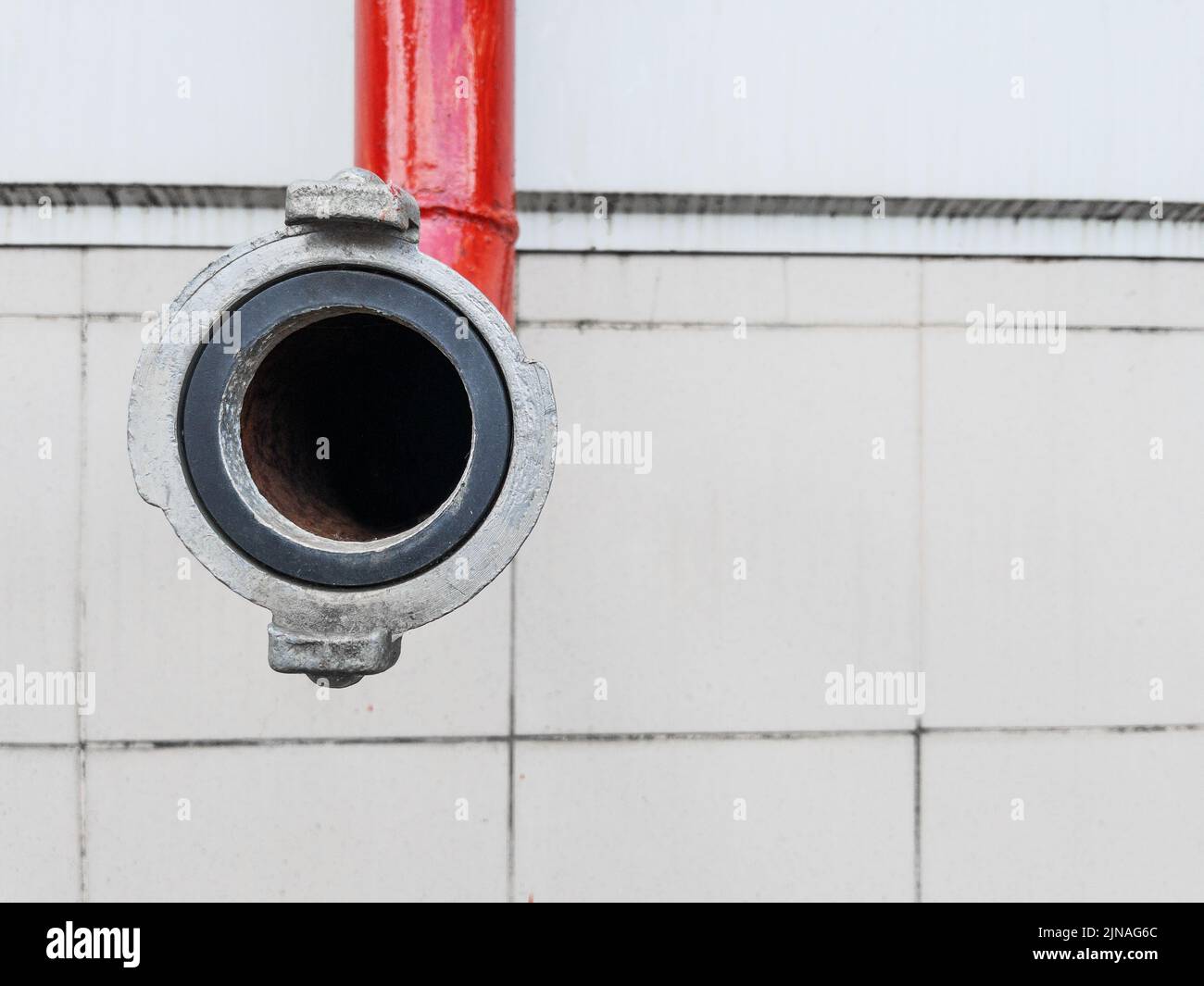 Red fire-fighting pipeline with a lock close-up on a tile background ...