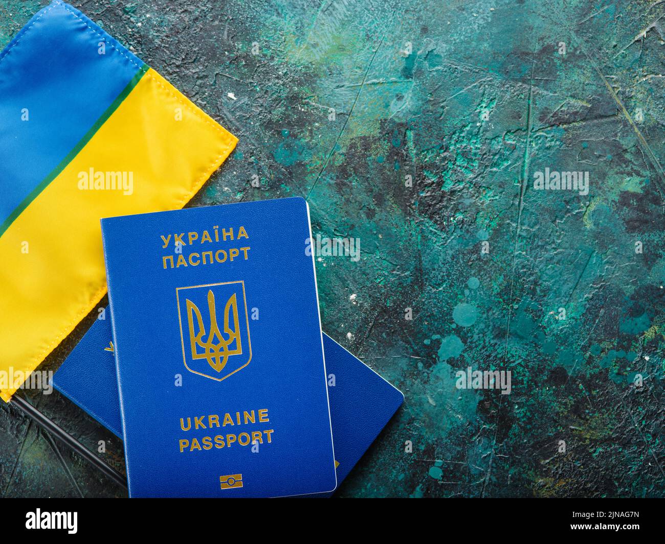 Blue Ukrainian biometric passports and Ukrainian flag on a dark ...