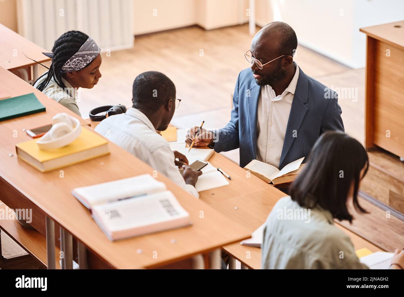 Teacher giving advice to student in his task while they sitting at desk ...
