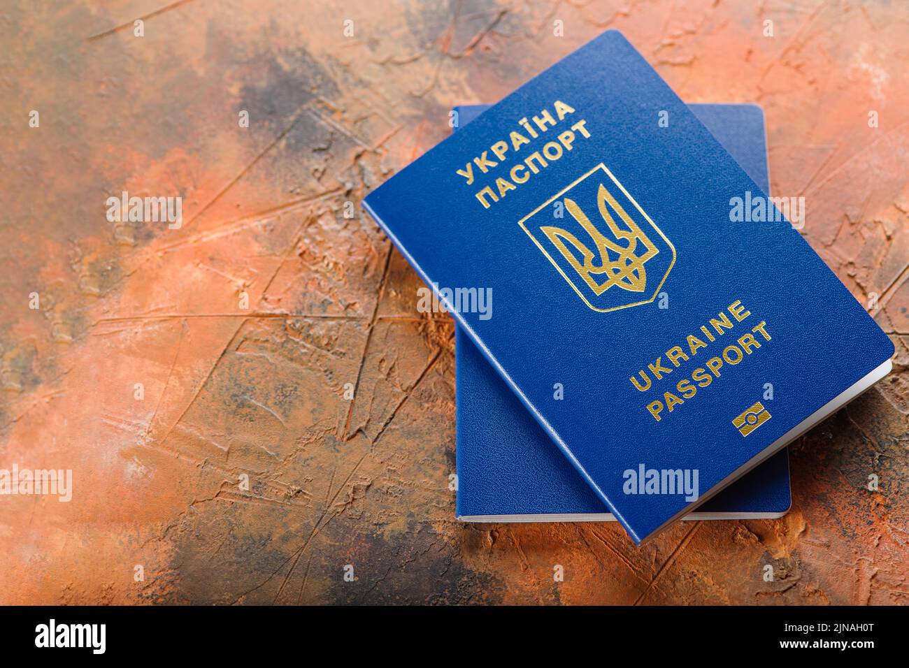 Two blue biometric passports of citizens of Ukraine on an orange marble ...