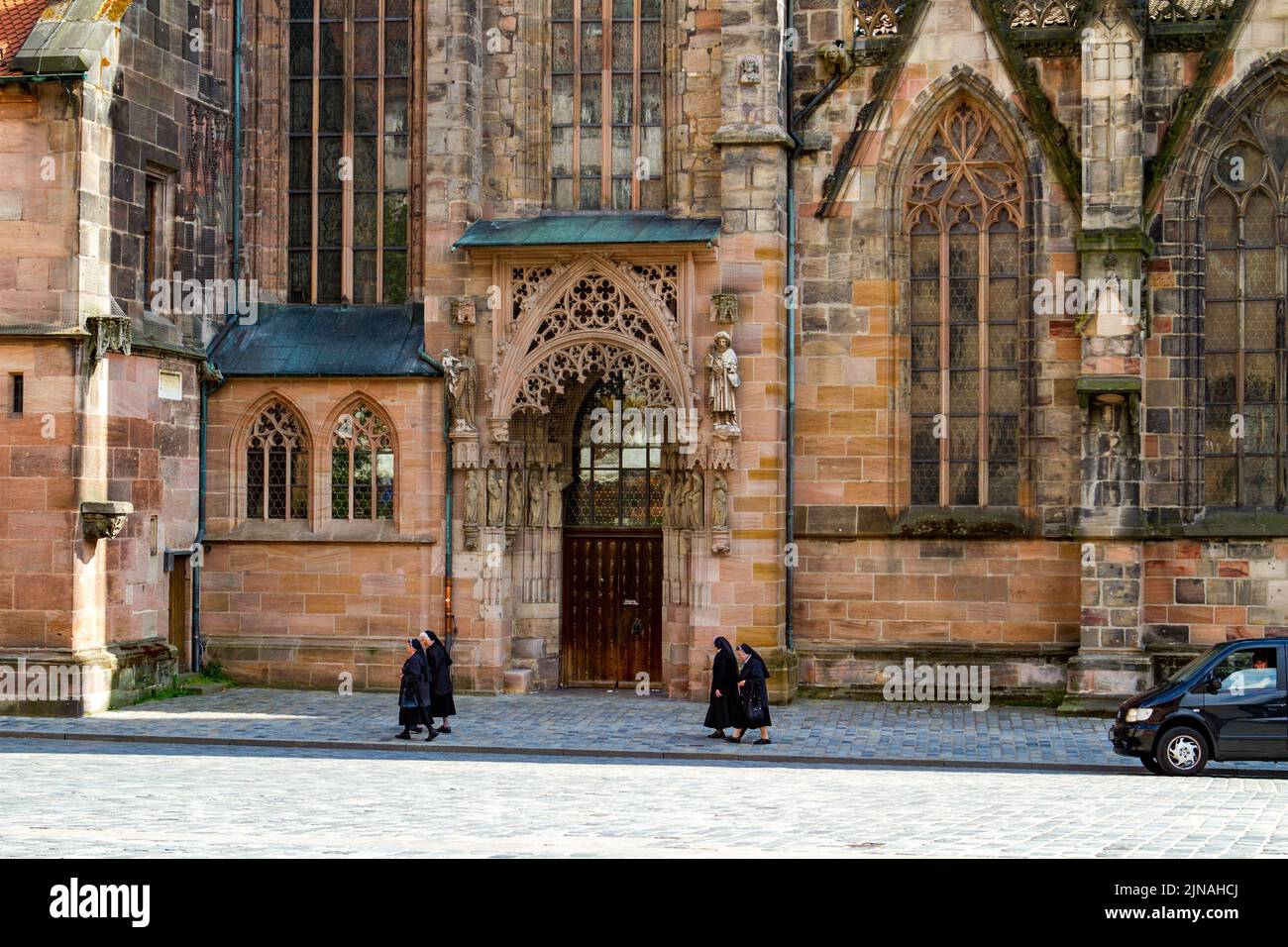 Catholic nuns walking in front of St. Lorenz (St. Lawrence), a medieval ...